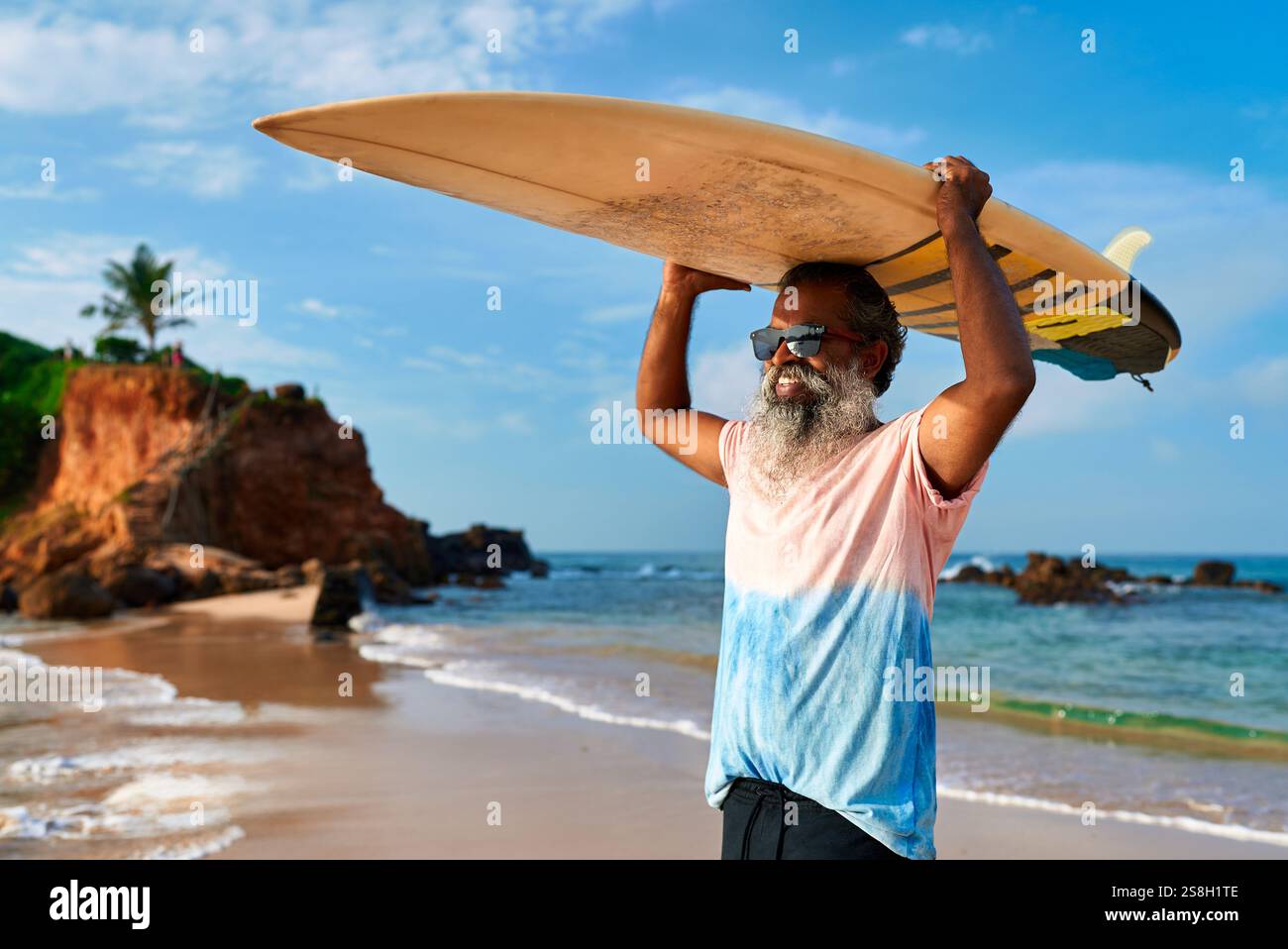 Senior man carries surfboard at beach. Active lifestyle for elderly ...