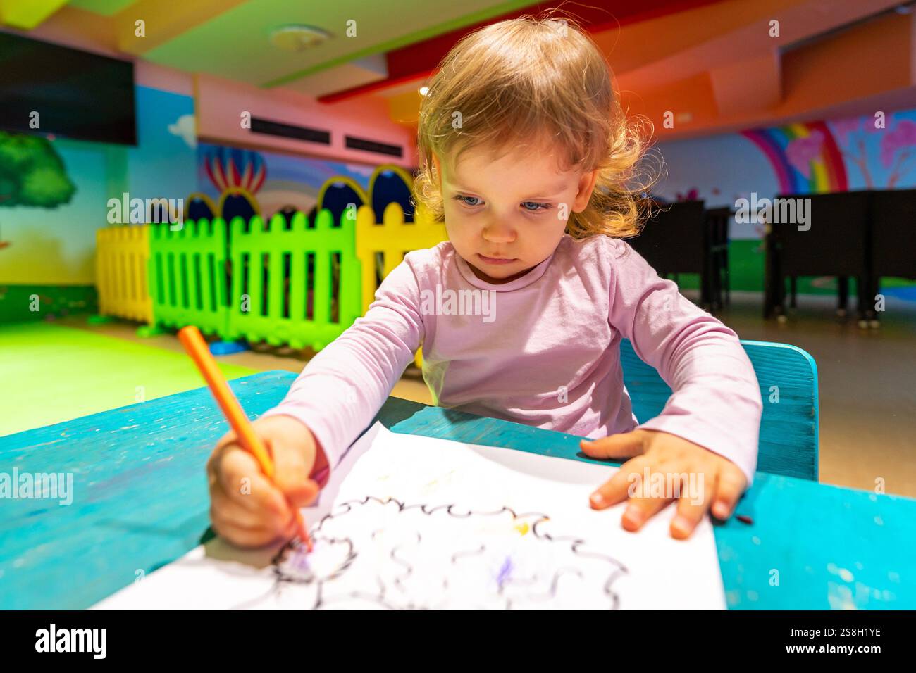 Focused toddler drawing in a colorful and stimulating playroom ...