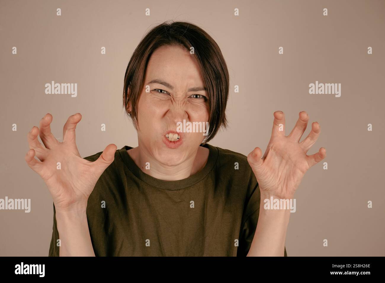 Mature brunette standing over gray background with disgusted expression ...