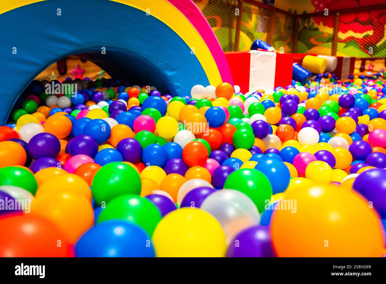 A vibrant ball pit filled with colorful balls and a rainbow soft ...