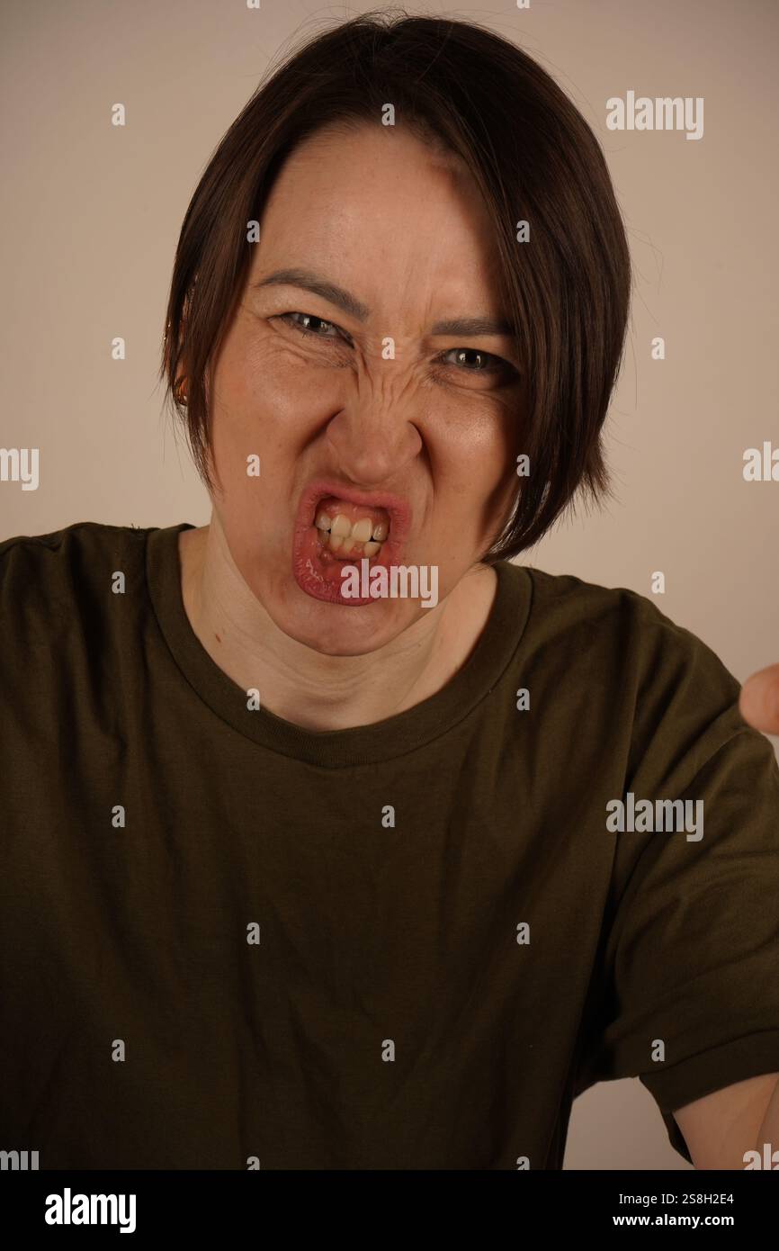 Young brunette woman standing over gray background with disgusted ...