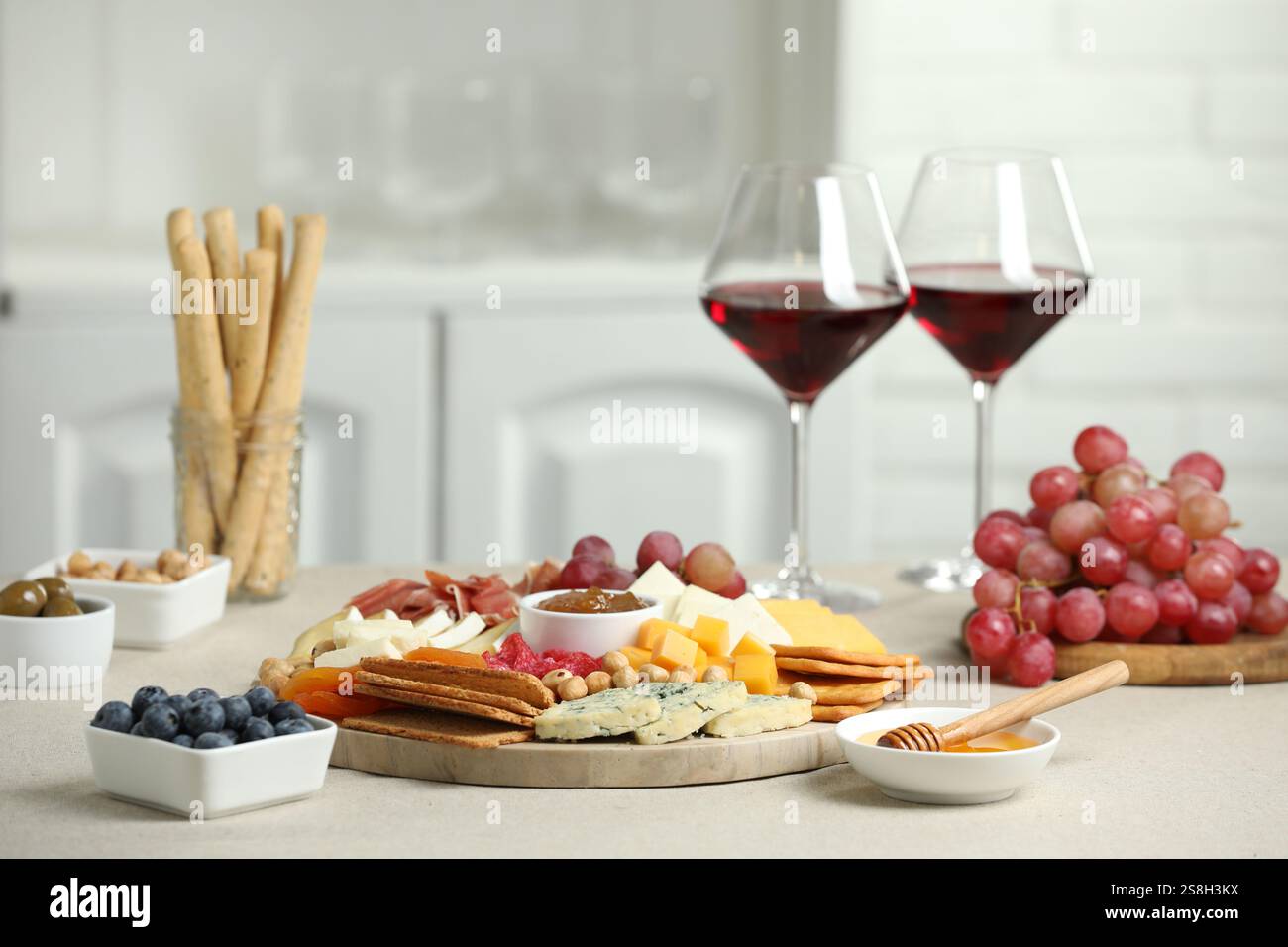 Different types of cut cheese and other snacks on light textured table ...