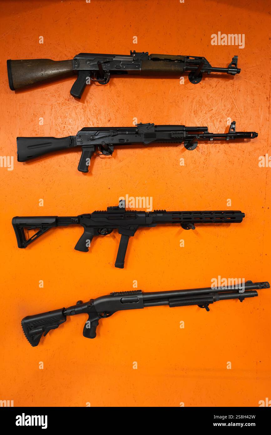 Various weapons hang on the orange wall in the shooting range, rifles ...