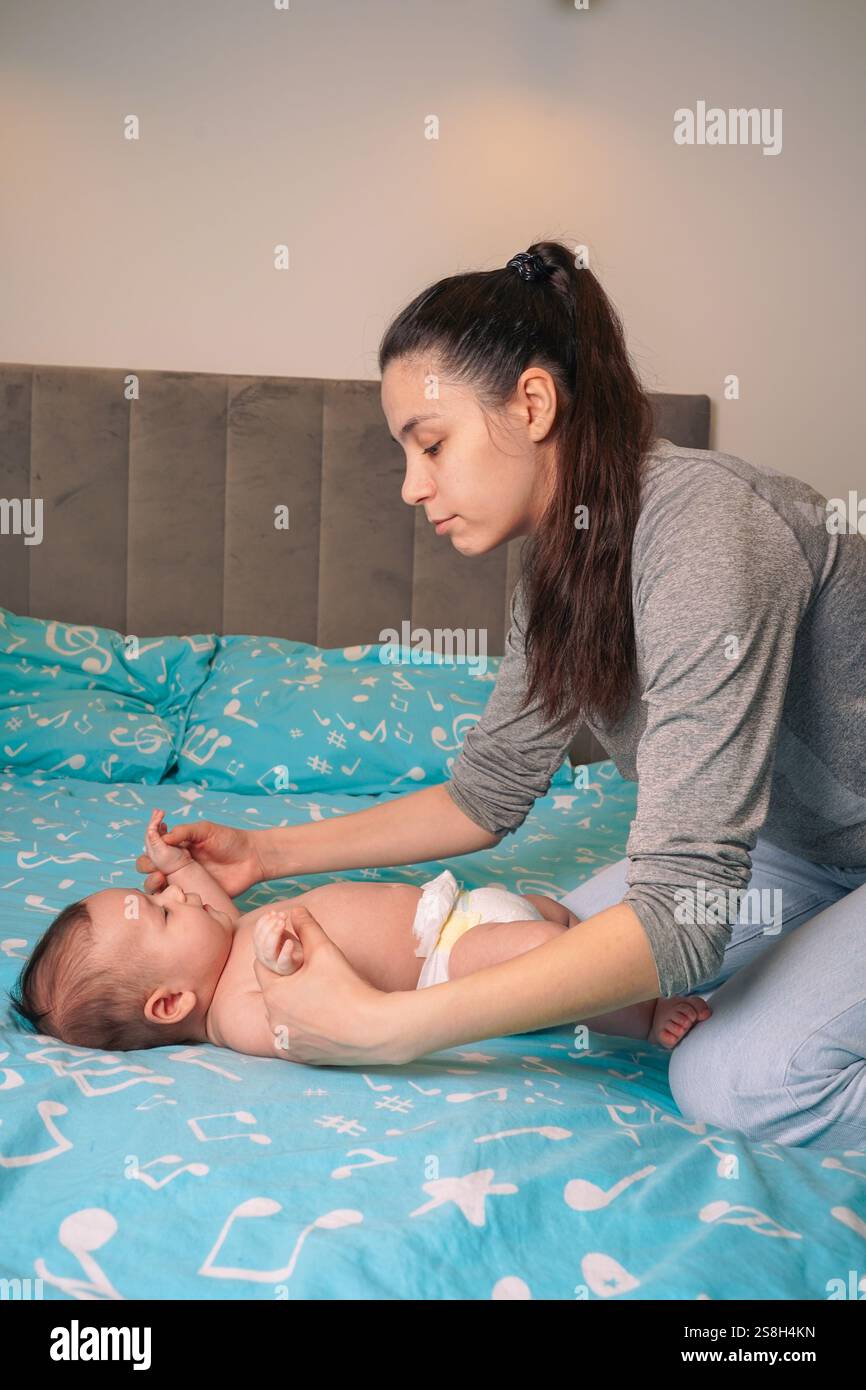 The baby lies on his back on a soft blue blanket, cooing softly as his ...