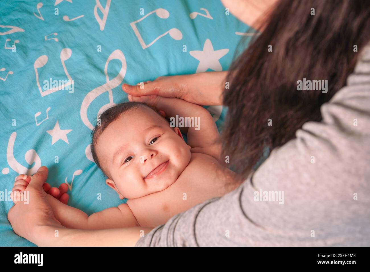 Happy boy giving baby massage to his mother at home. A newborn baby is ...