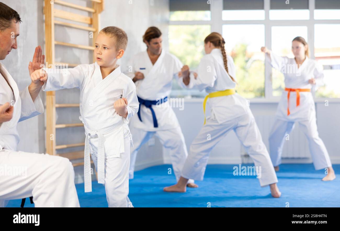 Boy at group training in gym practice karate punch block technique with ...