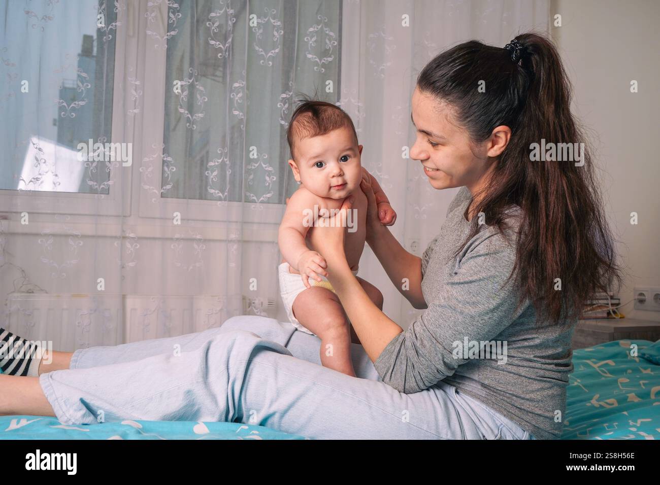 The baby, clad only in a diaper, looks at the camera with wide, curious ...