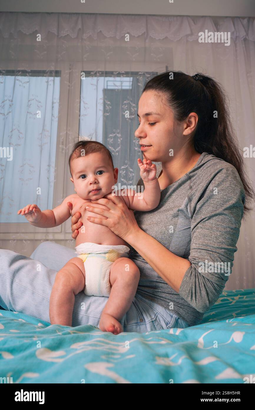 The baby stretches his arms upward, his little fists curling and ...
