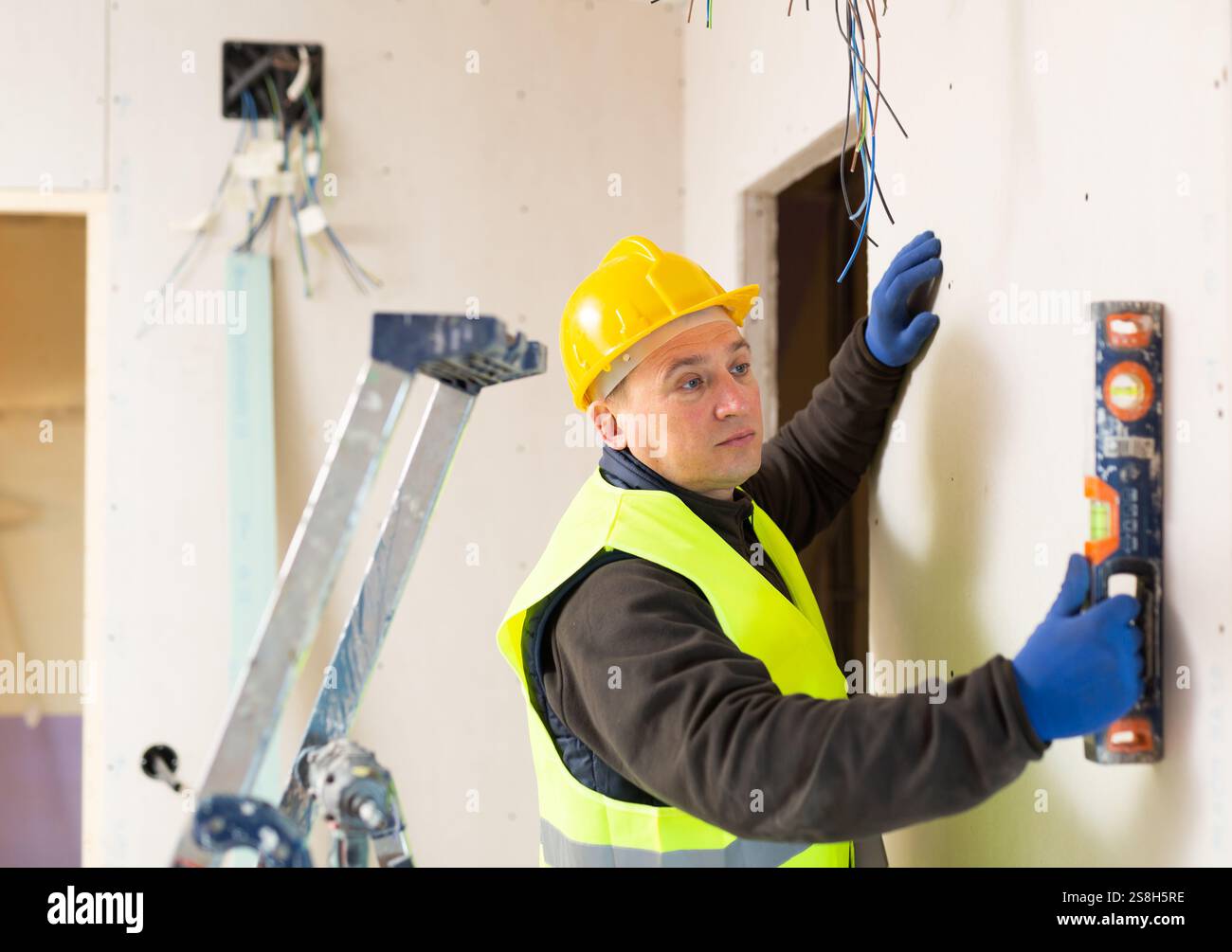 Repair man measuring evenness of wall Stock Photo - Alamy