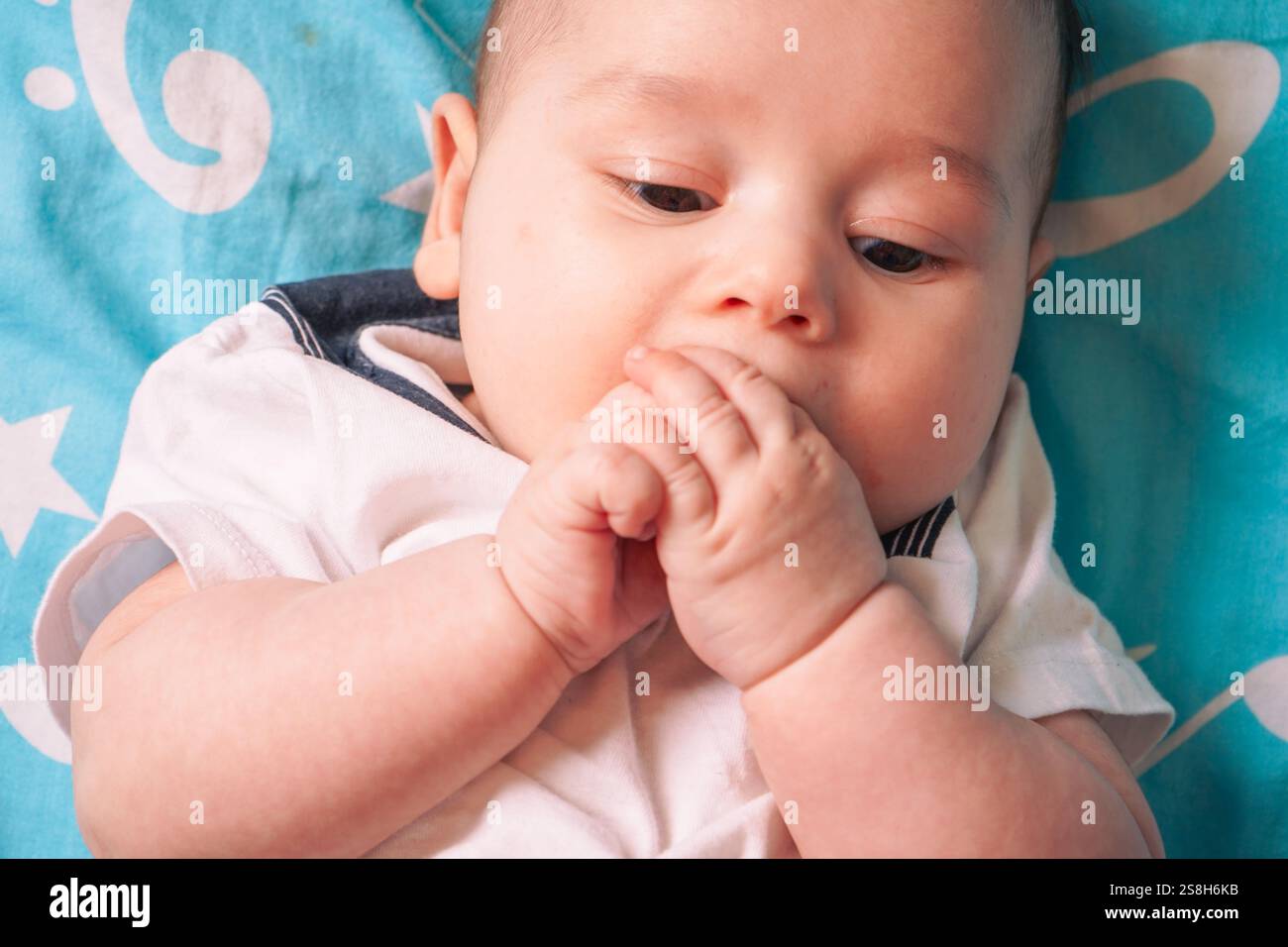 The baby stretches his arms upward, his tiny fists opening and closing ...