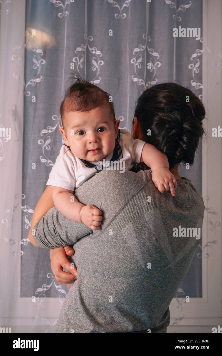Smiling mother hugs little newborn baby showing love. A young caring ...