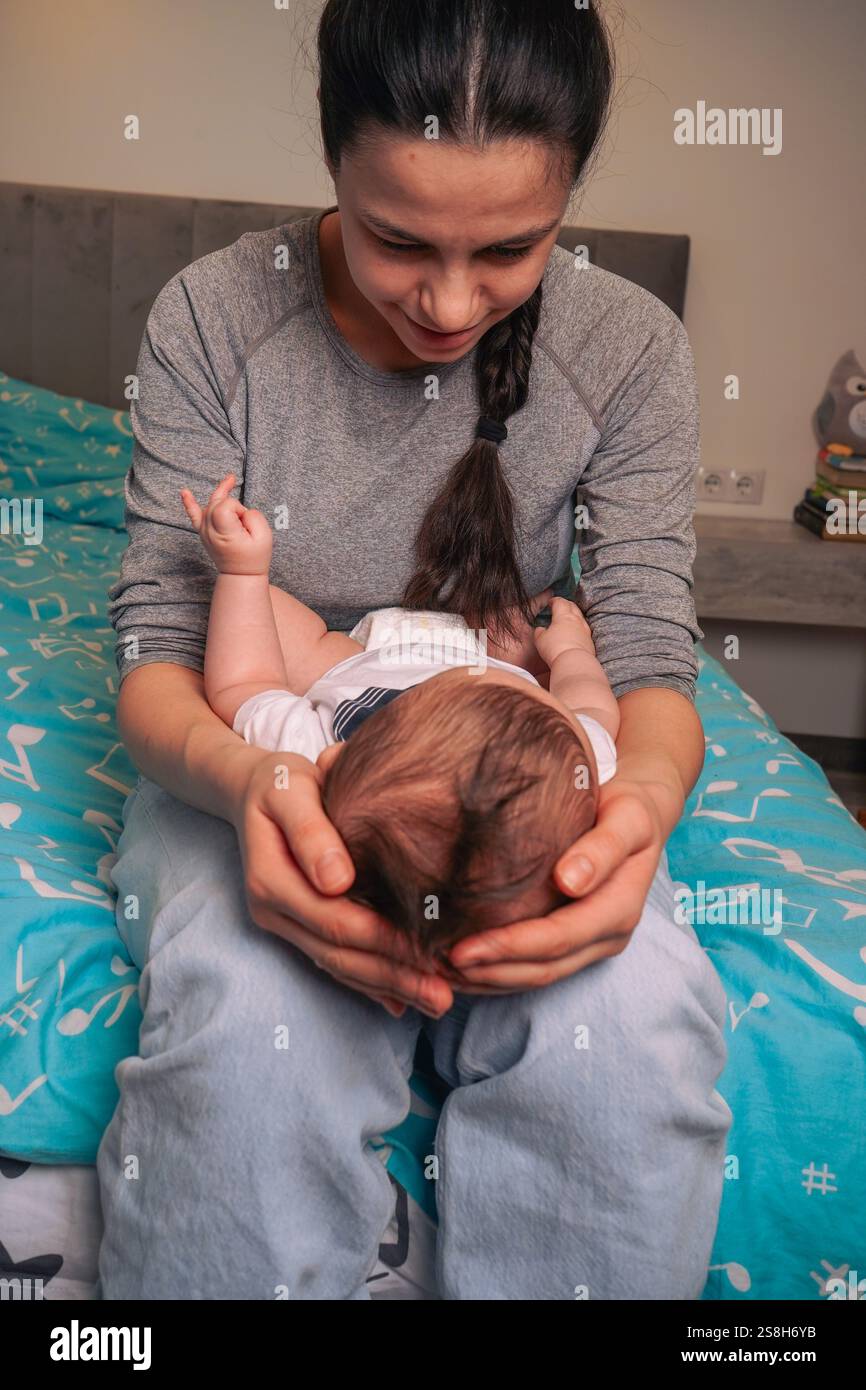 Mother cradling her crying newborn in her arms, gently holding the baby ...