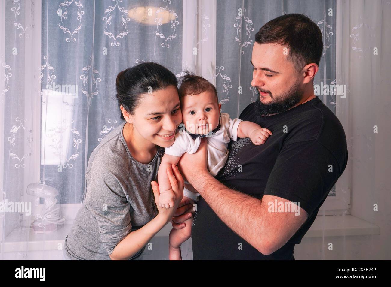 Loving mom and dad are holding a newborn baby in their arms. Father and ...