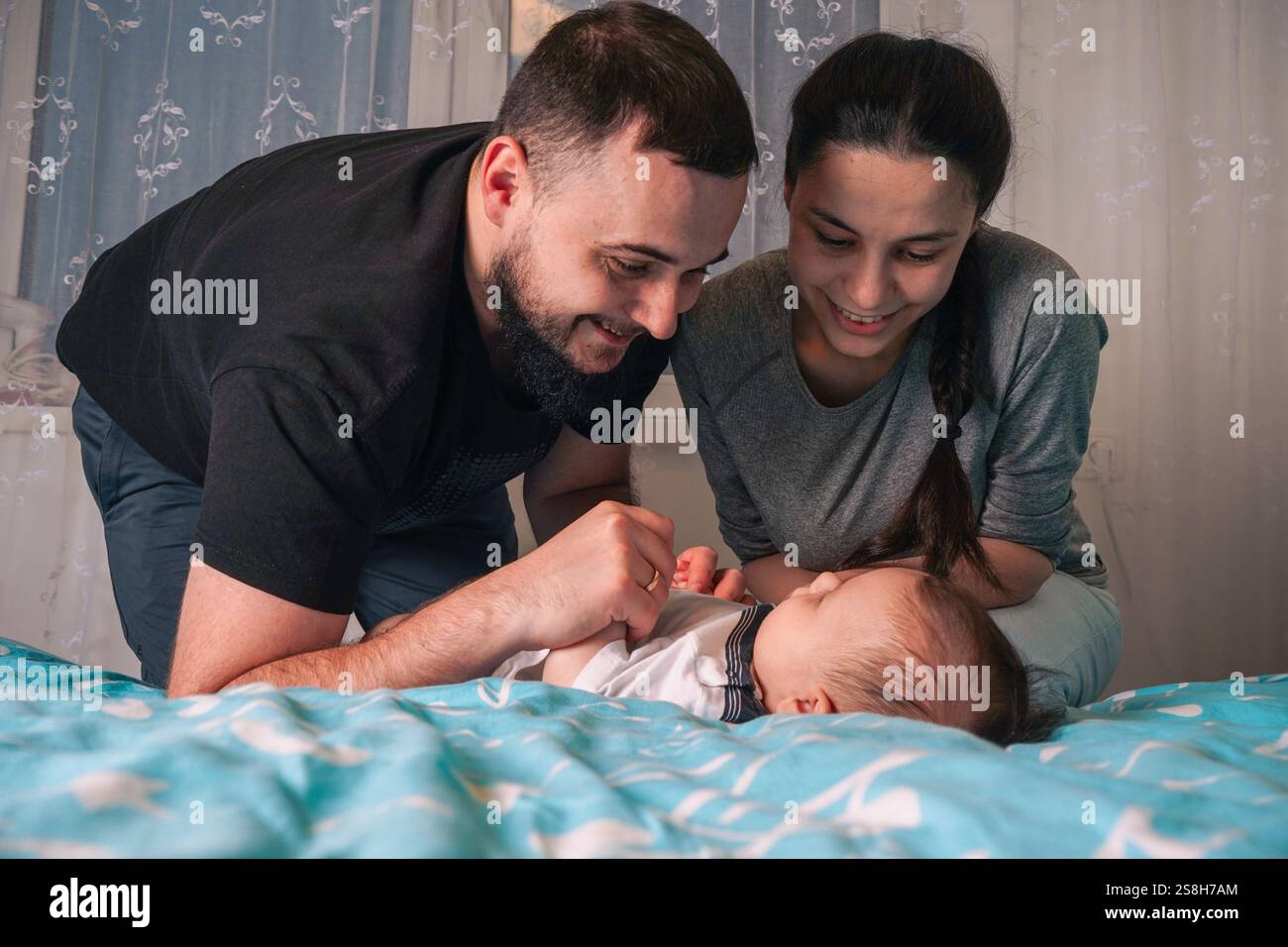 The concept of family love shines as a mother and father lean over ...