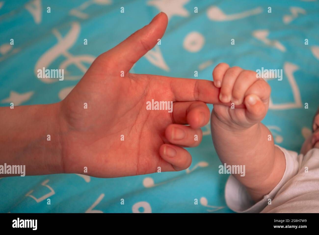 The baby grips a parent's finger with all its strength, a sweet ...
