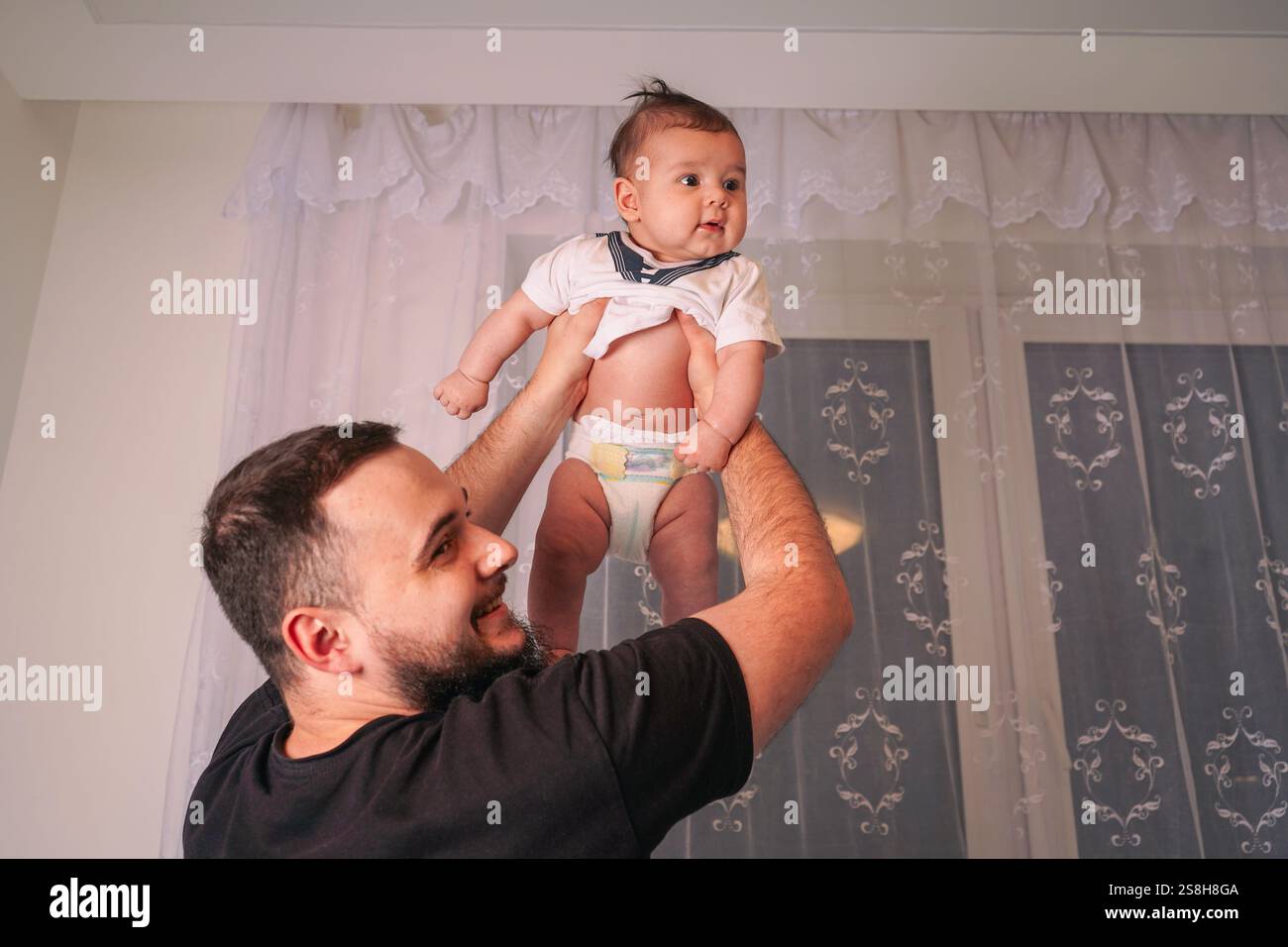 A delighted child reaches for the sky, and the father lifts it high up ...