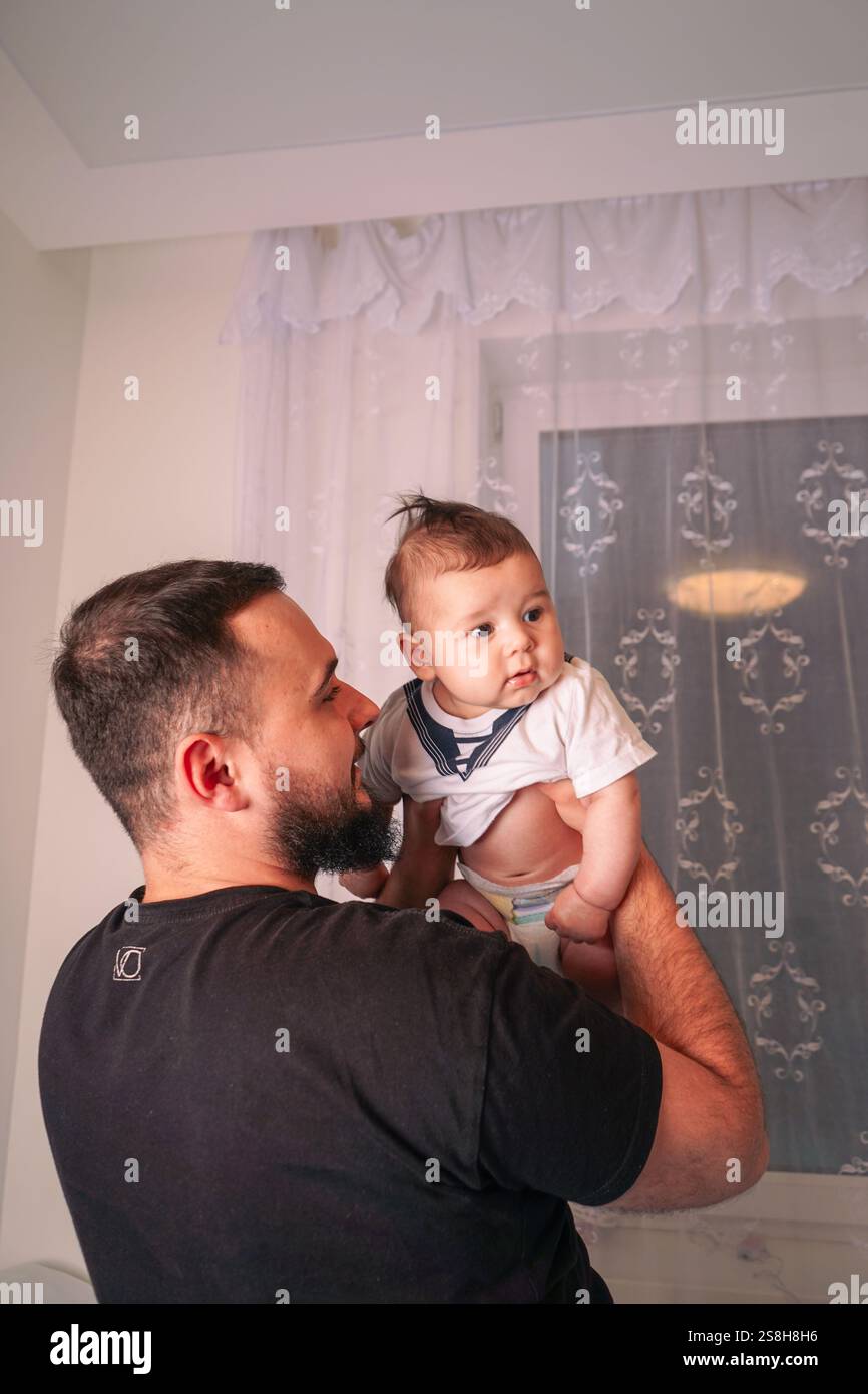 The father gazes proudly at his baby while lifting them above hi Stock ...