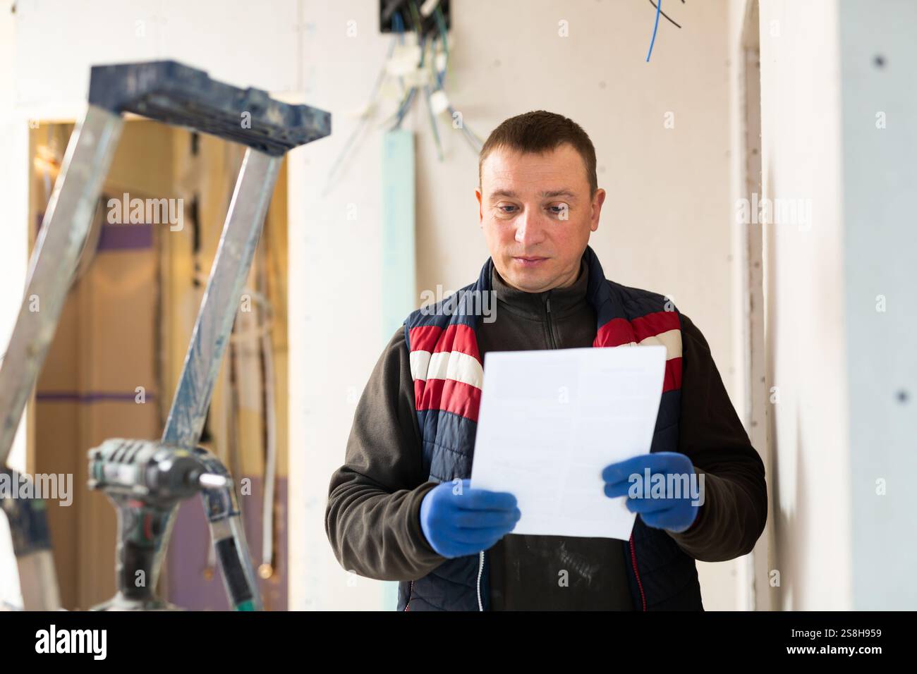 Repair man standing in apartment and checking documentation Stock Photo ...