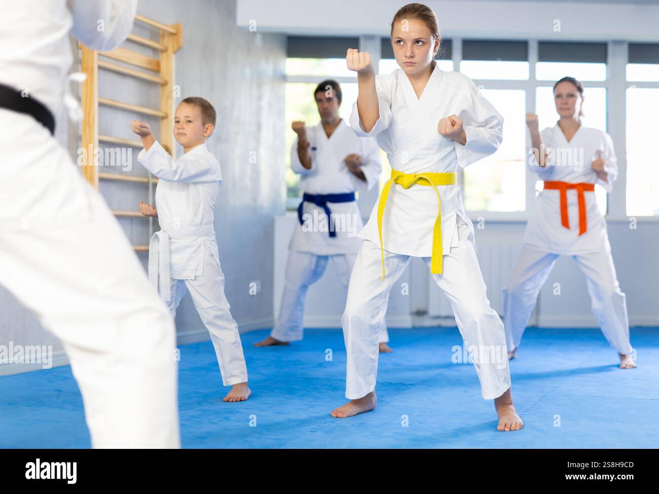 Teen girl with family repeat movements and learn fighting techniques during martial arts lesson ...