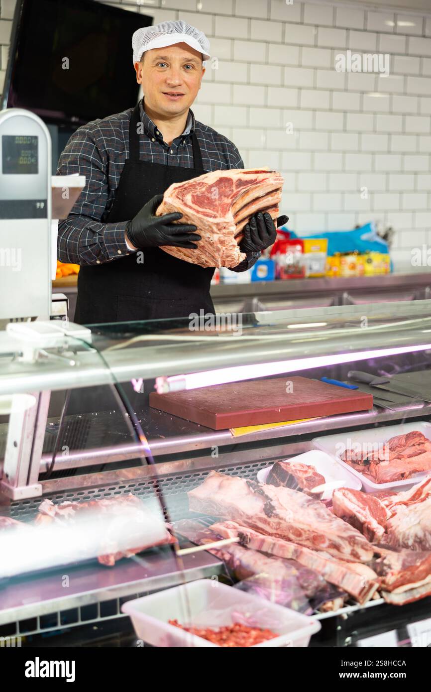 Adult man puts beef ribs in showcase Stock Photo - Alamy