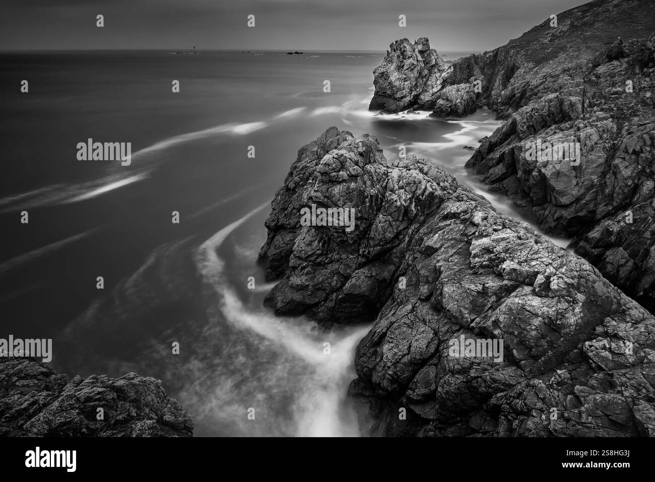 Rugged granite sea cliffs, with blurred long exposure sea, on the South ...