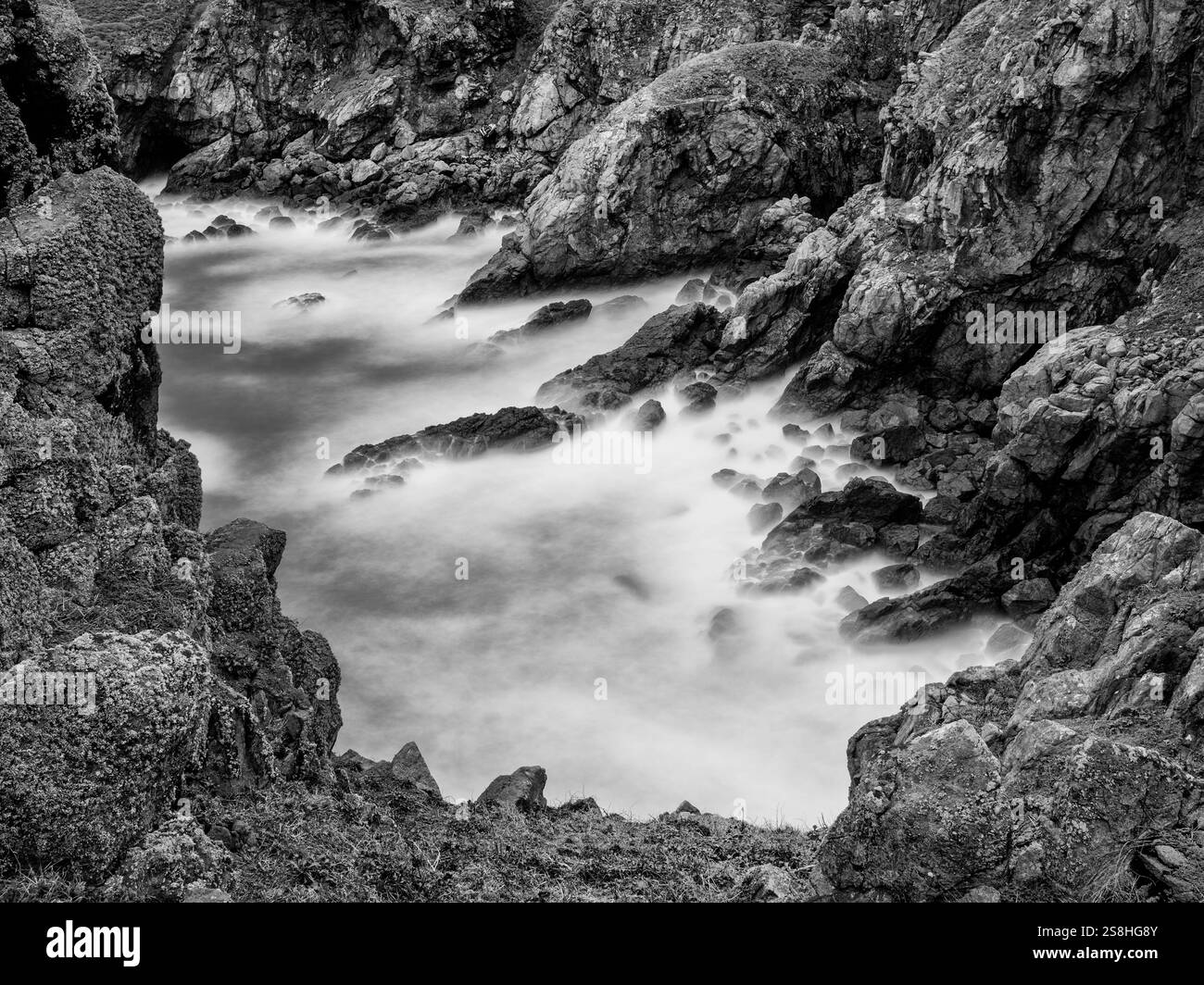Rugged granite sea cliffs, with blurred long exposure sea, on the South ...