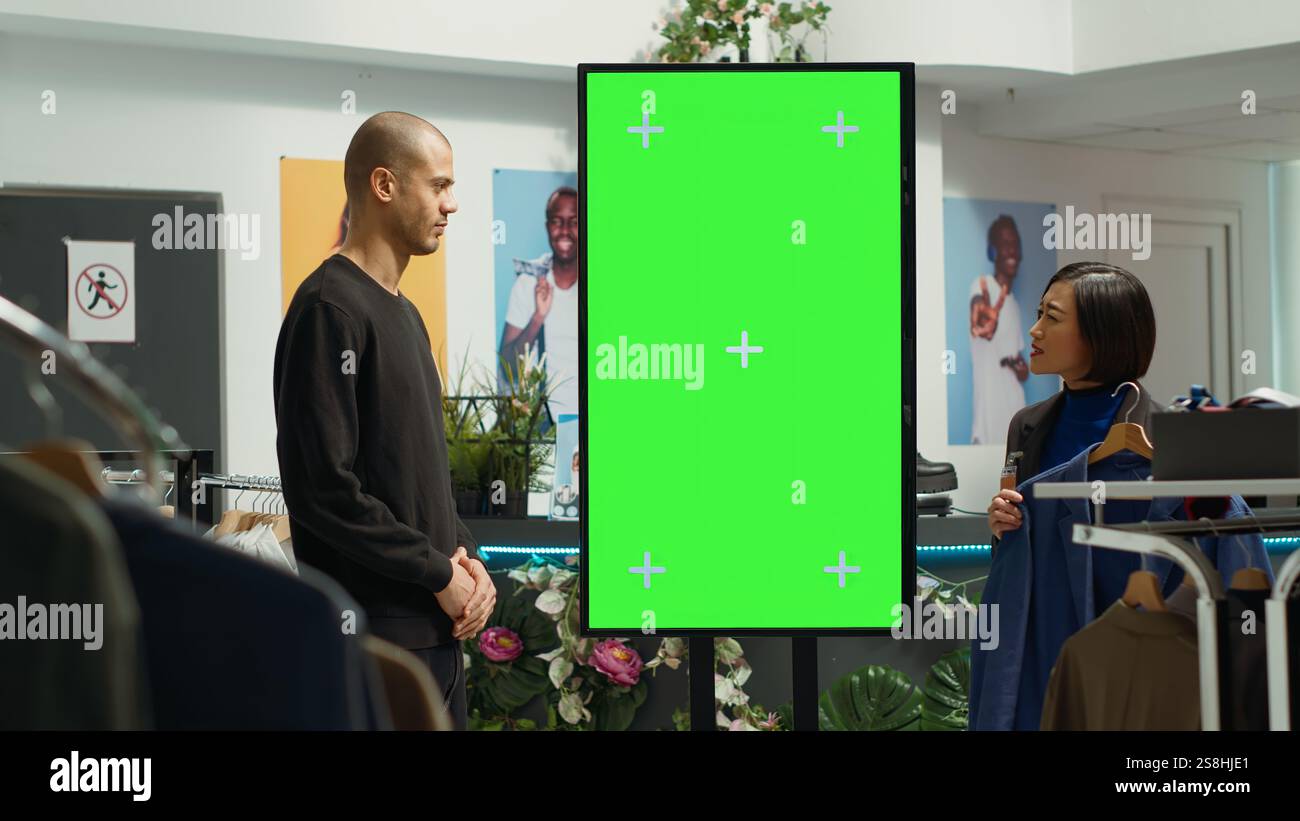 Asian store assistant next to green screen presenting the new clothes ...