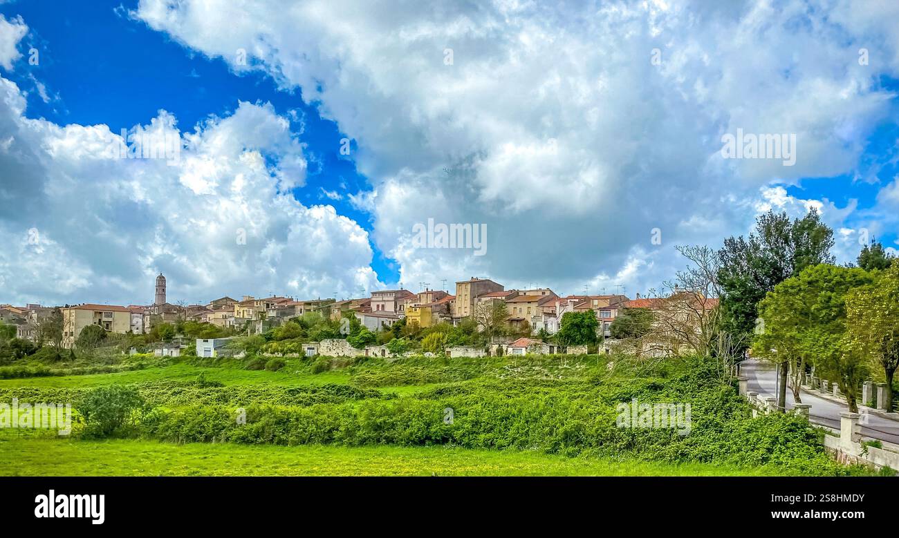 Town view, town wall and church tower of Thiesi, blue sky with clouds ...