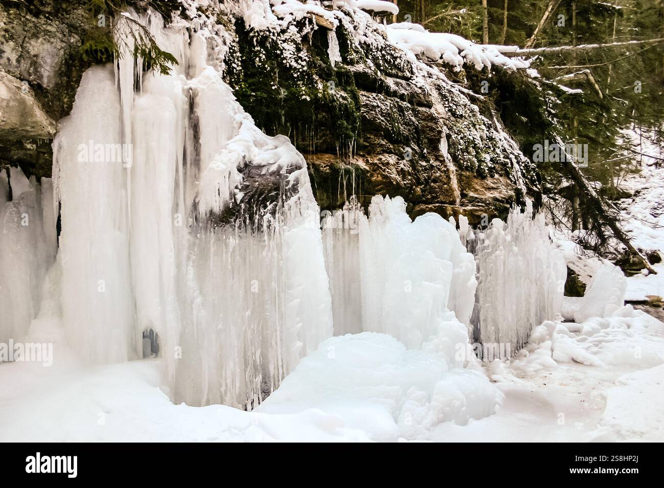 A frozen waterfall with ice and snow. The ice is piled up on the side ...