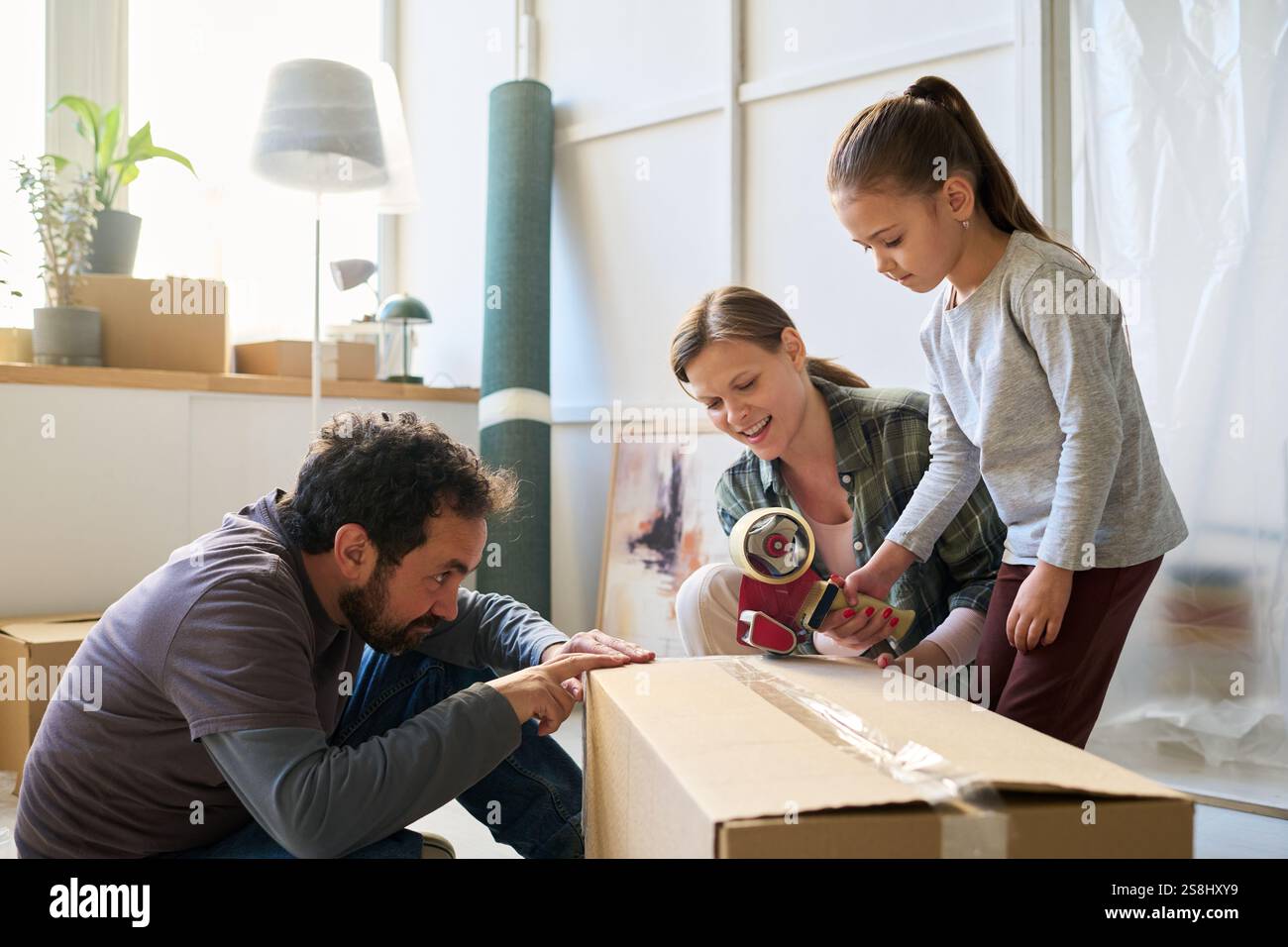 Young man and woman packing and sealing boxes with fragile objects with ...