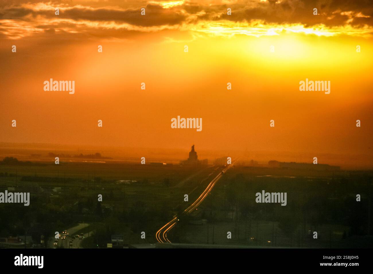 A sunset over a road with a large building in the distance. The sky is ...