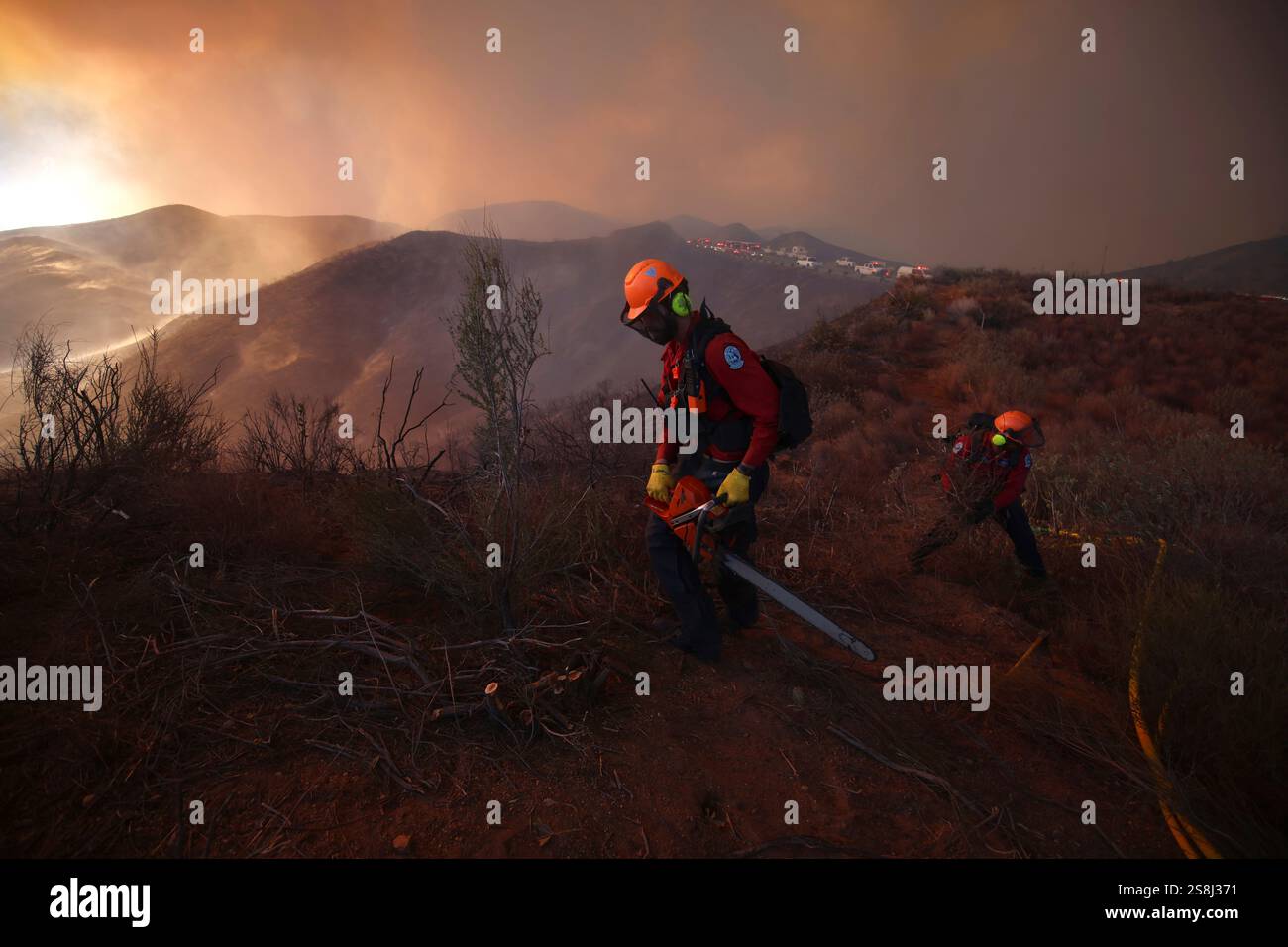 A firefighter looking out towards Lake Castaic stands on a mound ...