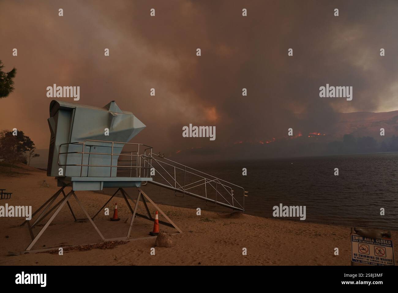 Flames caused by the Hughes Fire is seen along Castaic Lake in Castaic ...
