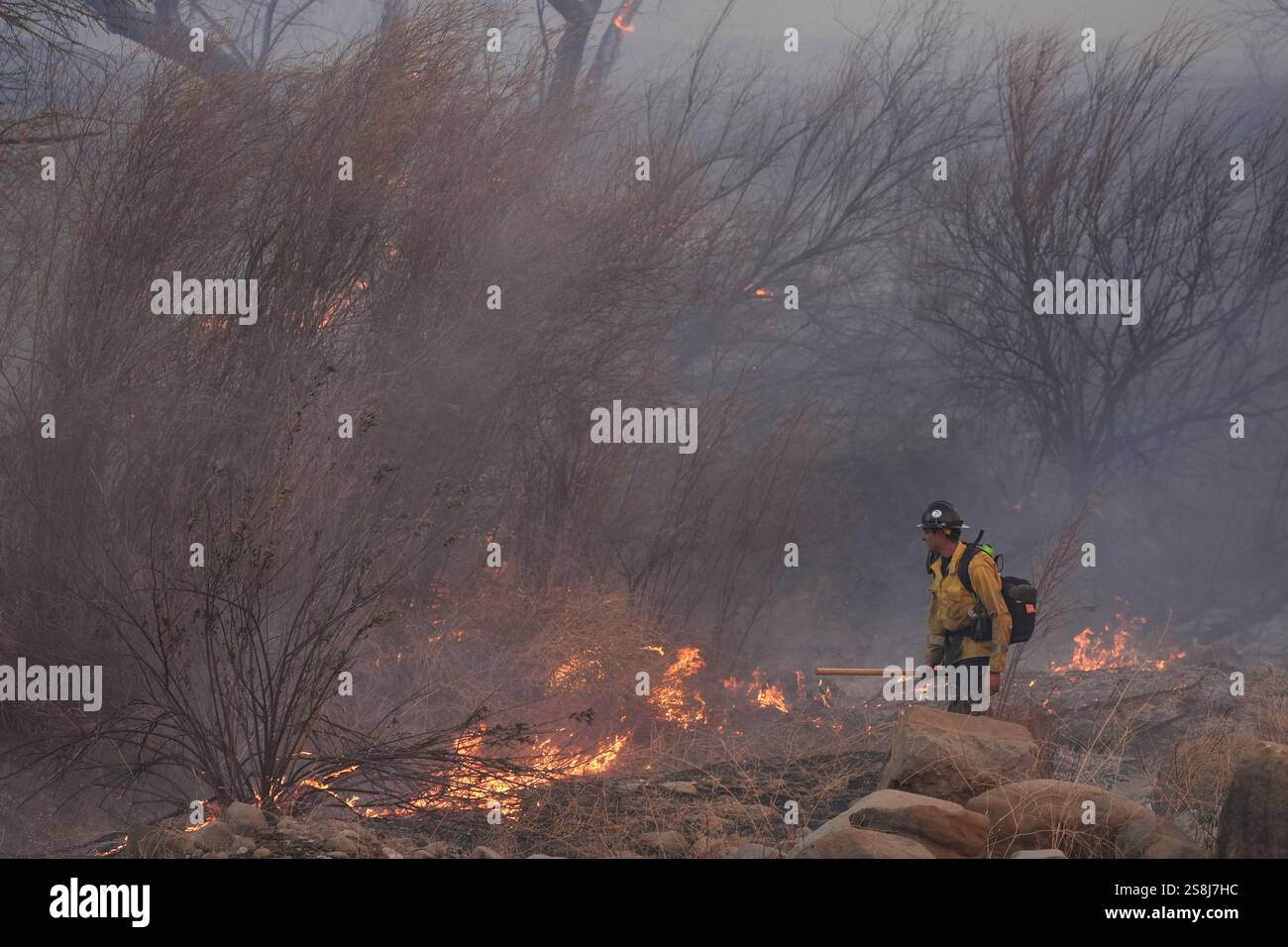 A firefighter monitors flames caused by the Hughes Fire is seen along ...