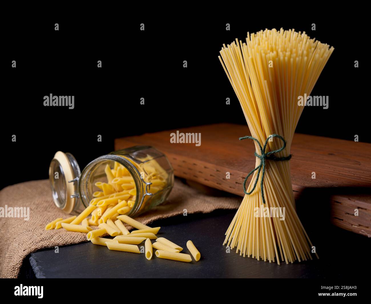 A still life photo of dried spaghetti noodles standing up and penne ...