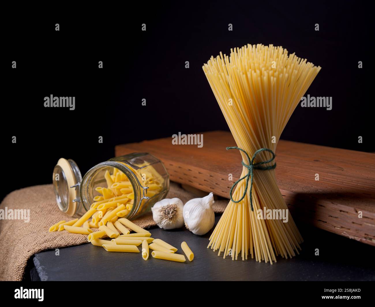 A still life photograph of dried penne pasta in a glass jar, dried ...