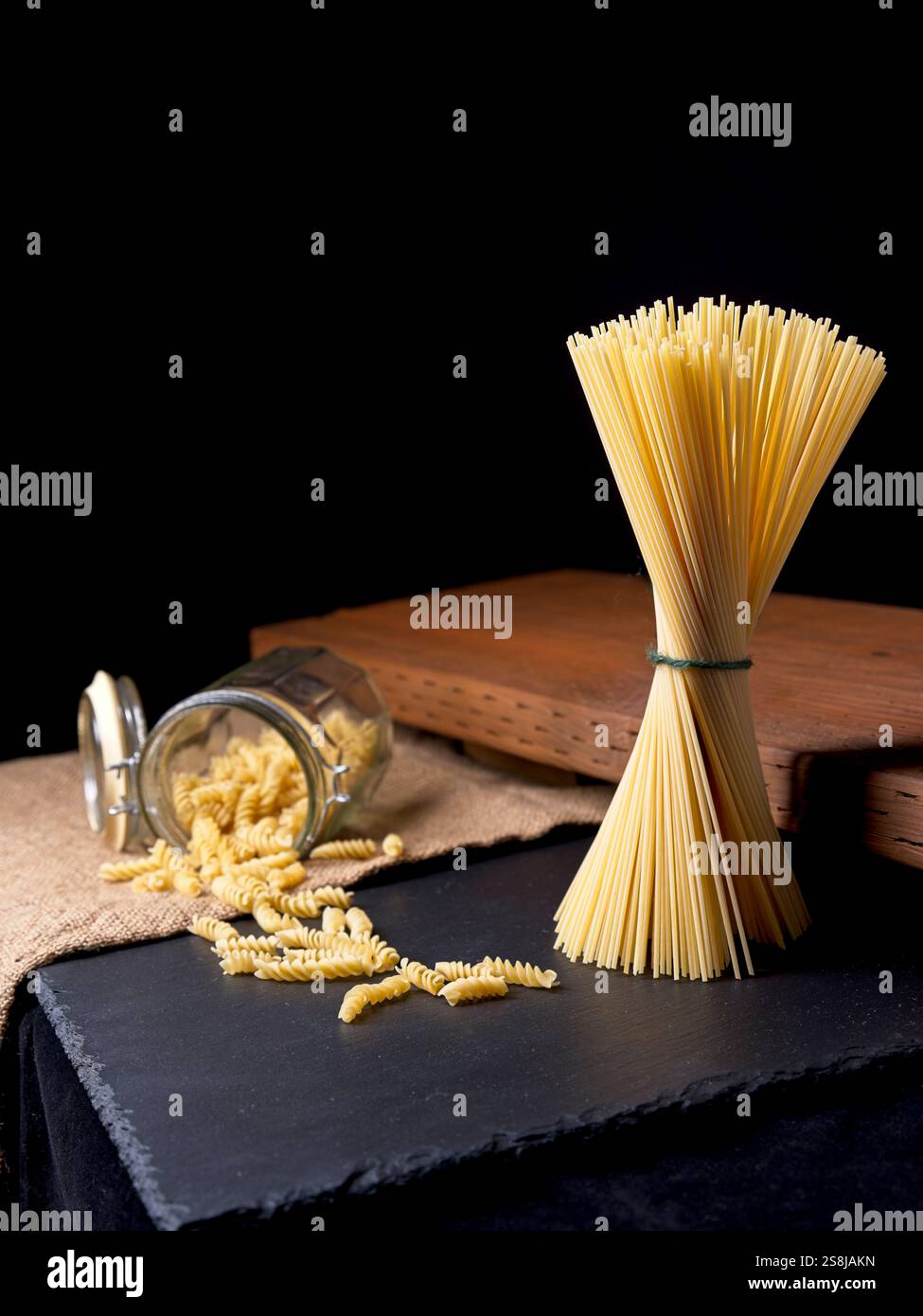 A still life photo of dried spaghetti noodles standing up and spiral ...
