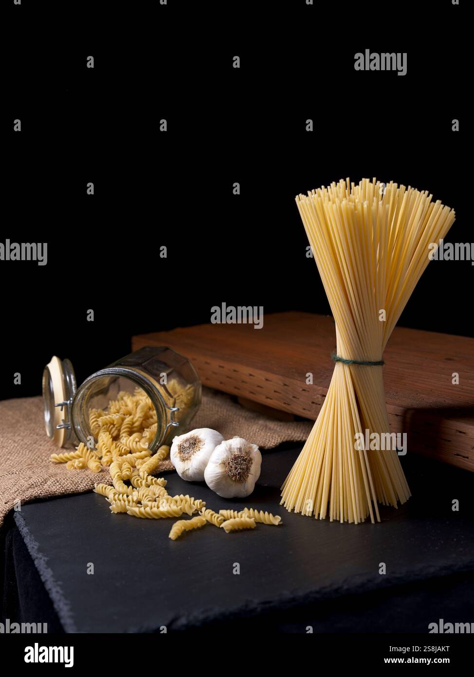A still life photo of dried spaghetti and spiral noodles with two bulbs ...