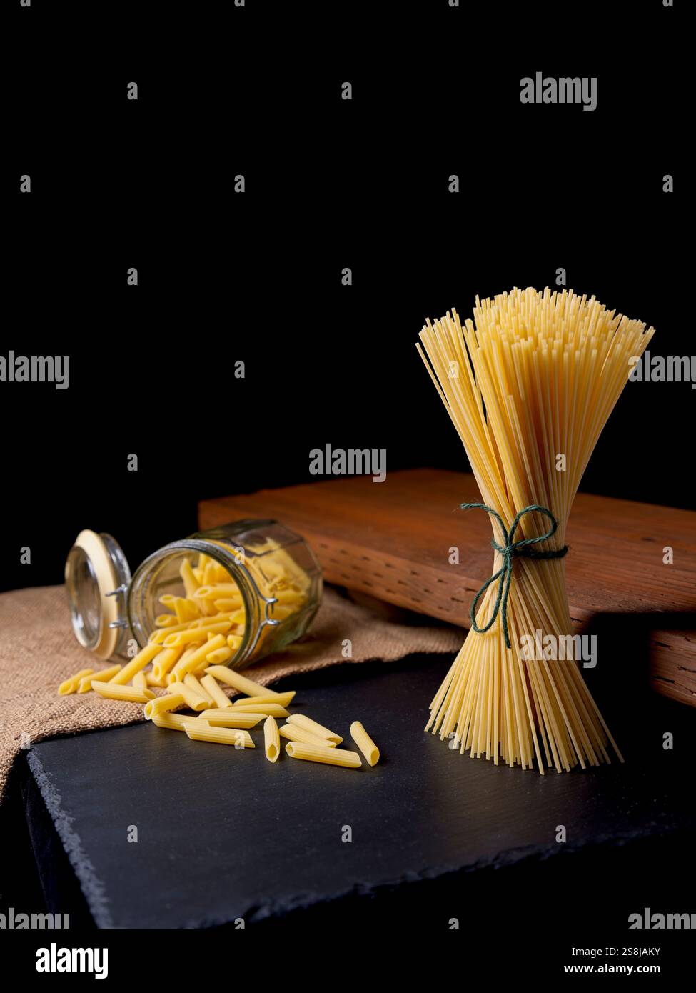 A still life photo of dried spaghetti noodles standing up and penne ...
