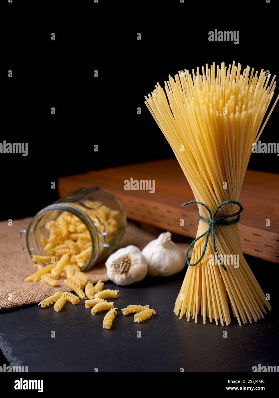 A still life photo of dried spaghetti and spiral noodles with two bulbs ...