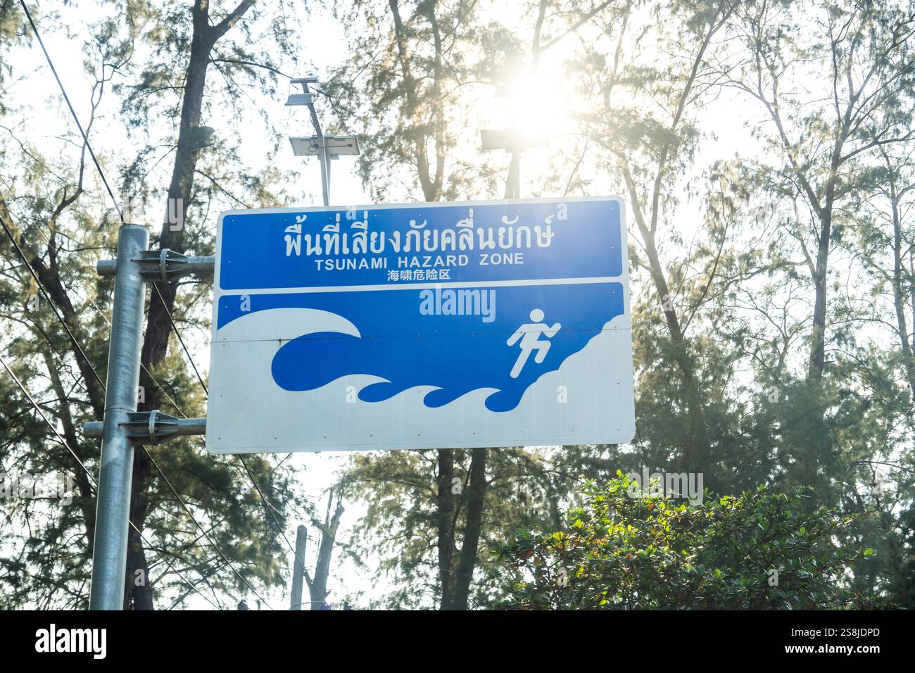 A clear warning sign marks a tsunami hazard zone, showing a running ...