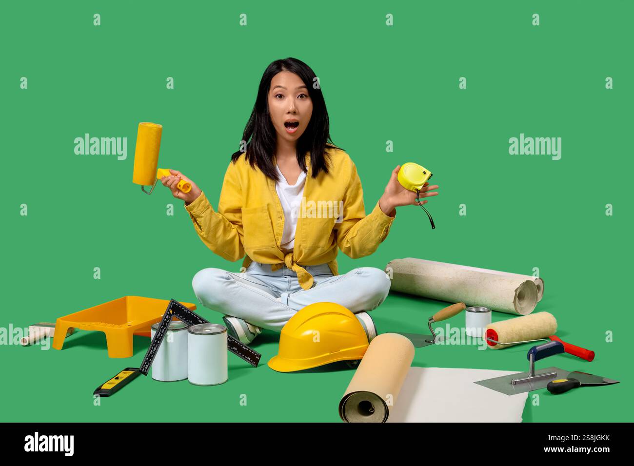 Asian decorator with tools sitting on green background Stock Photo - Alamy