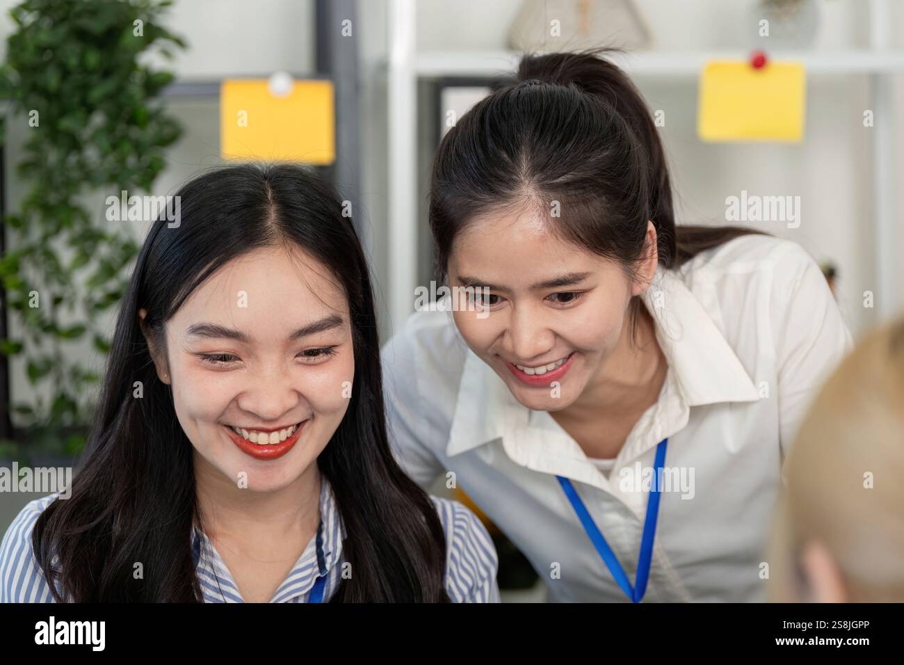 Two female professionals collaborating and laughing during a successful ...