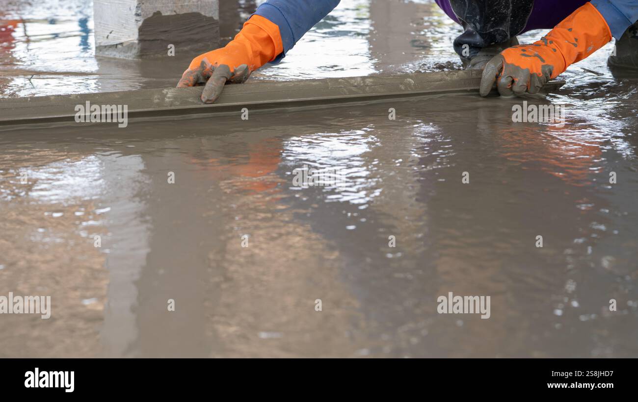 Mason worker working with trowel to level cement floor at construction ...