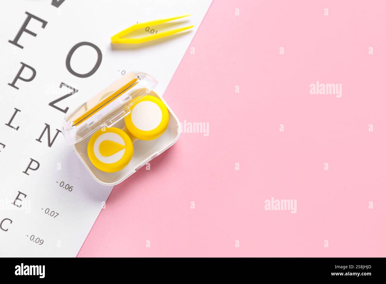 Eye test chart with tweezers and container for contact lenses on pink ...