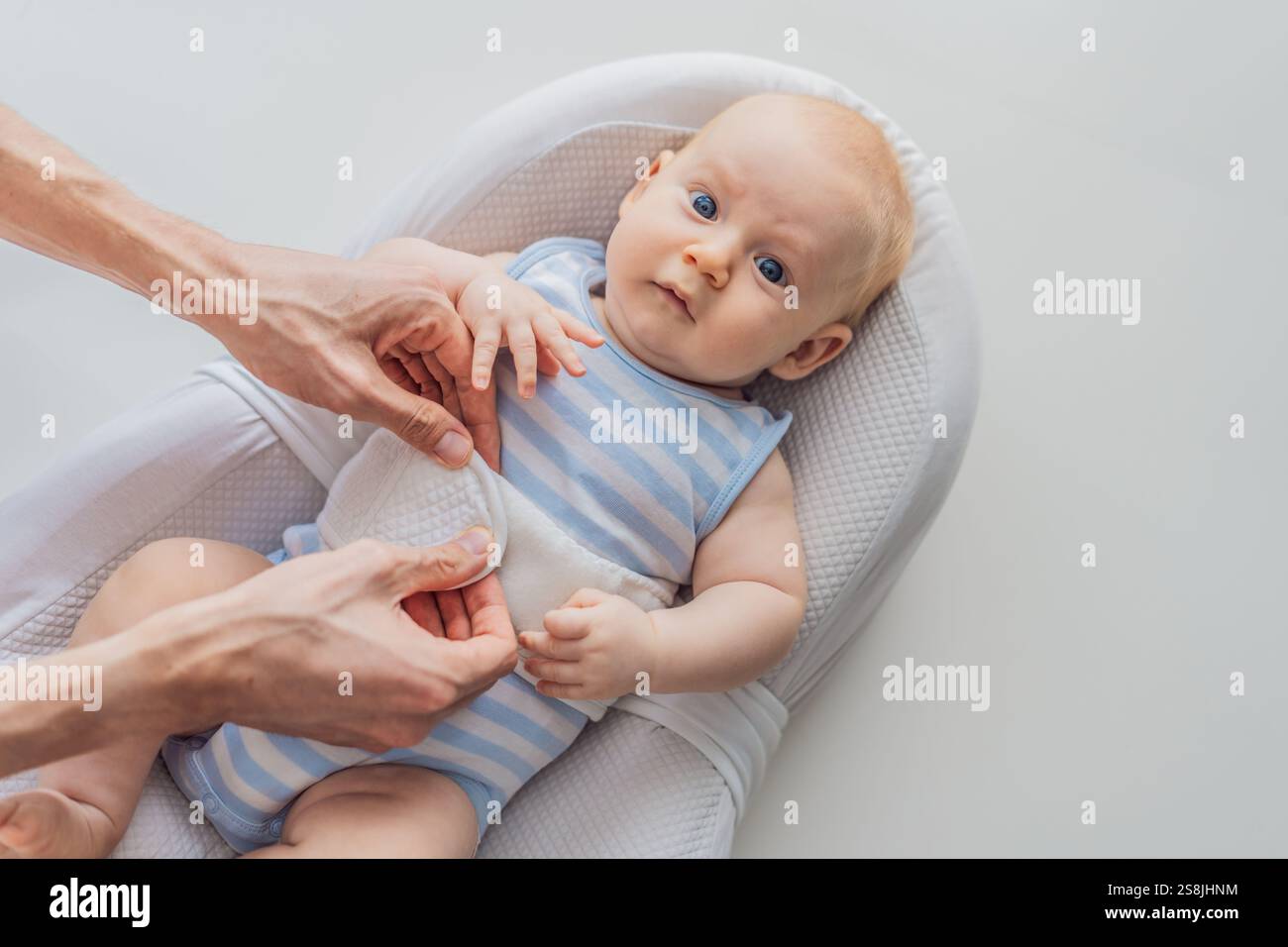 Adorable 3-month-old baby lying safely in a cozy infant cocoon secured ...