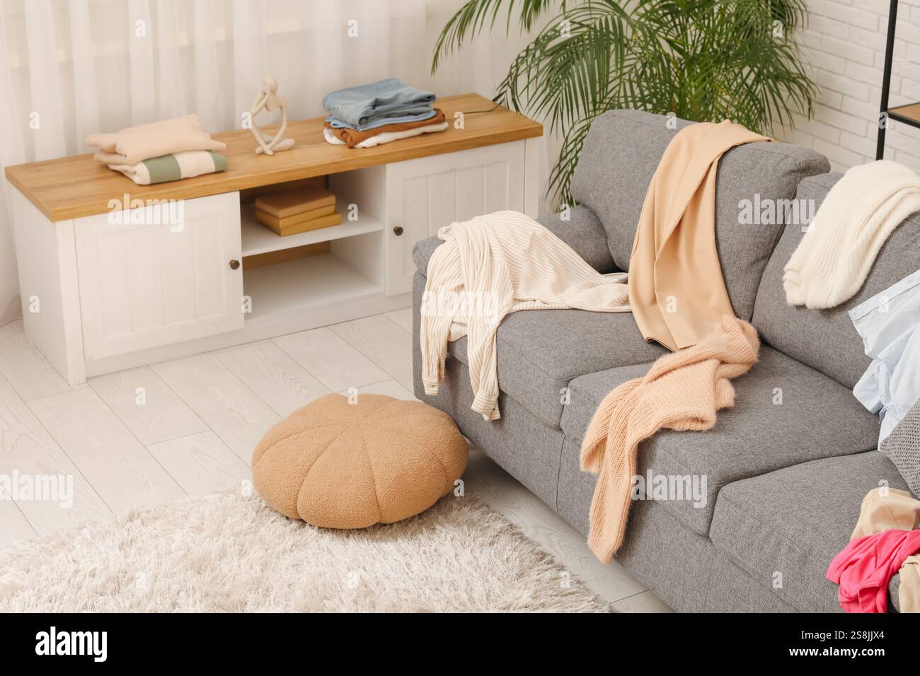 Interior of messy living room with grey sofa, commode and scattered ...