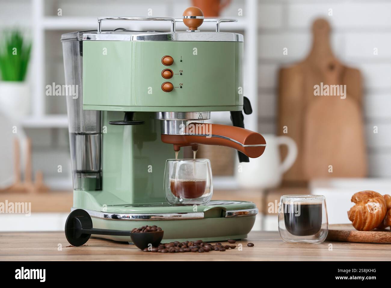 Modern coffee machine with glasses of hot espresso and plate of sweet ...