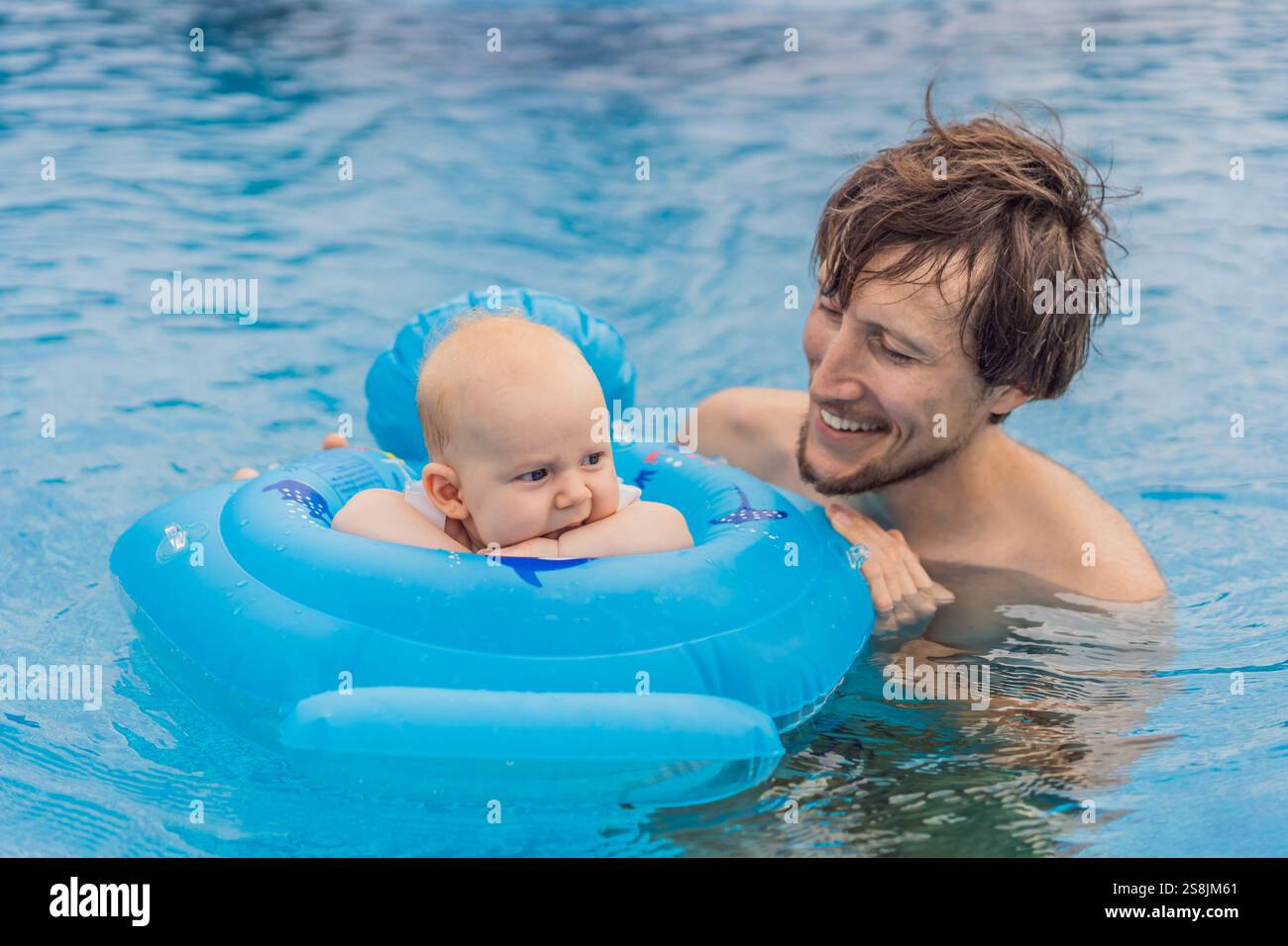 A father enjoys swimming in a pool with his son infant, who is safely ...