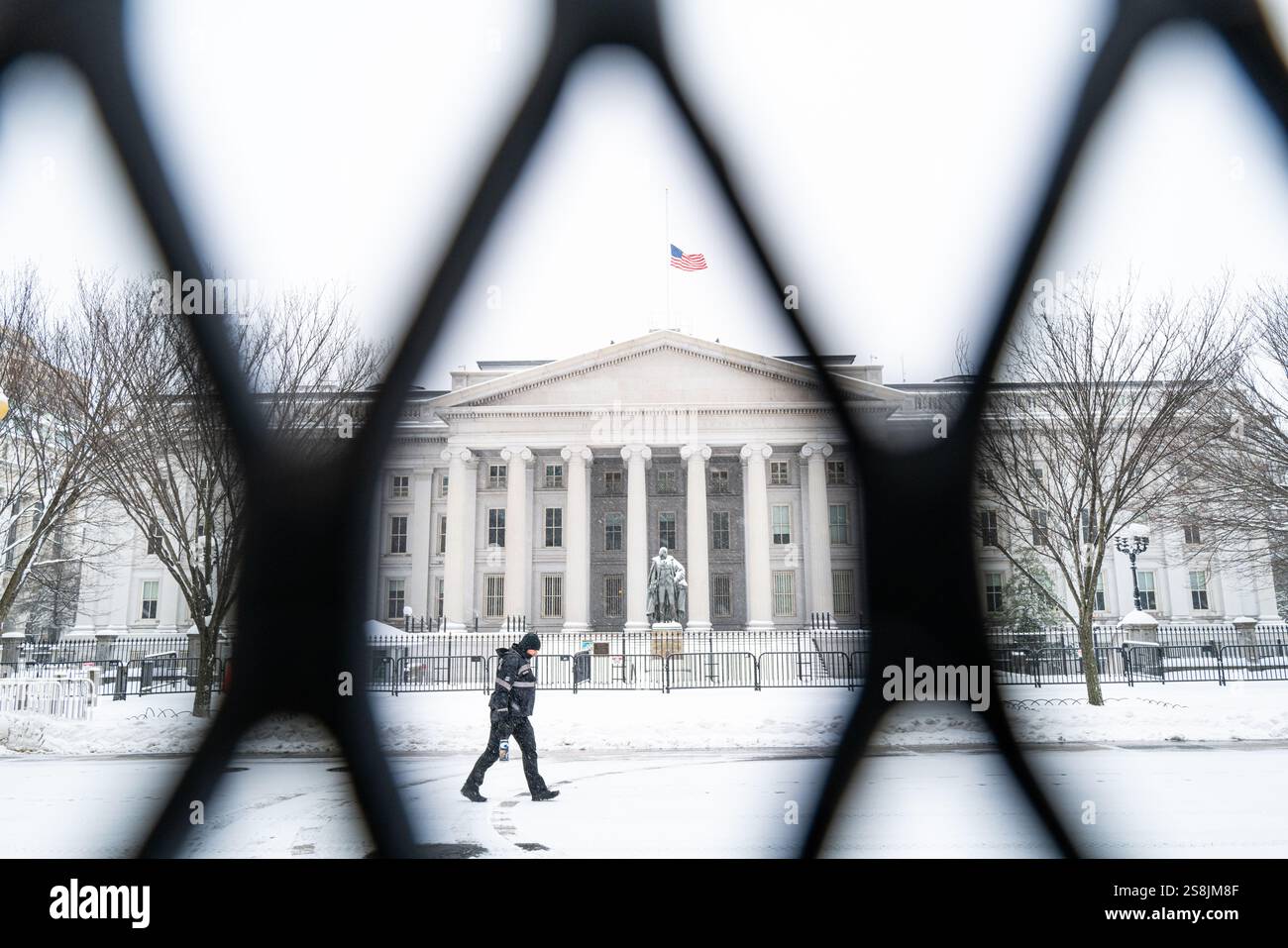 View through fencing of a secret service agent walking in a snowstorm ...